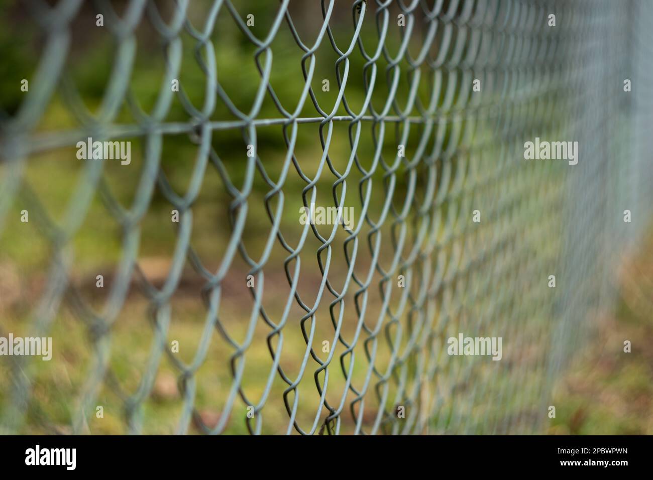Chain link mesh wire fence around a garden. Close up shot, shallow ...