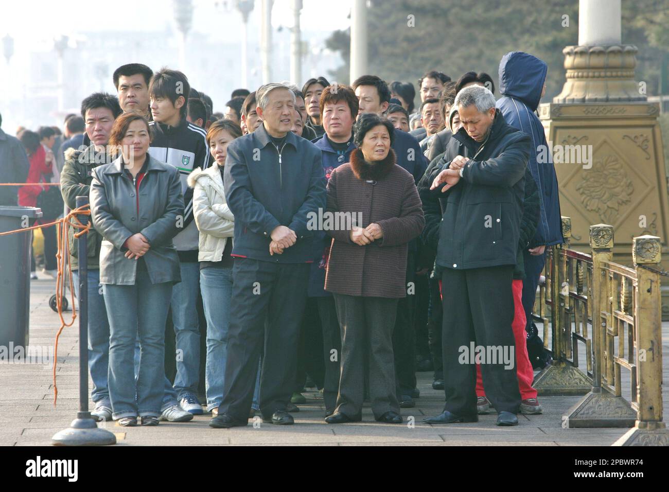 People stand in a queue as they wait for their turn to go in to the ...