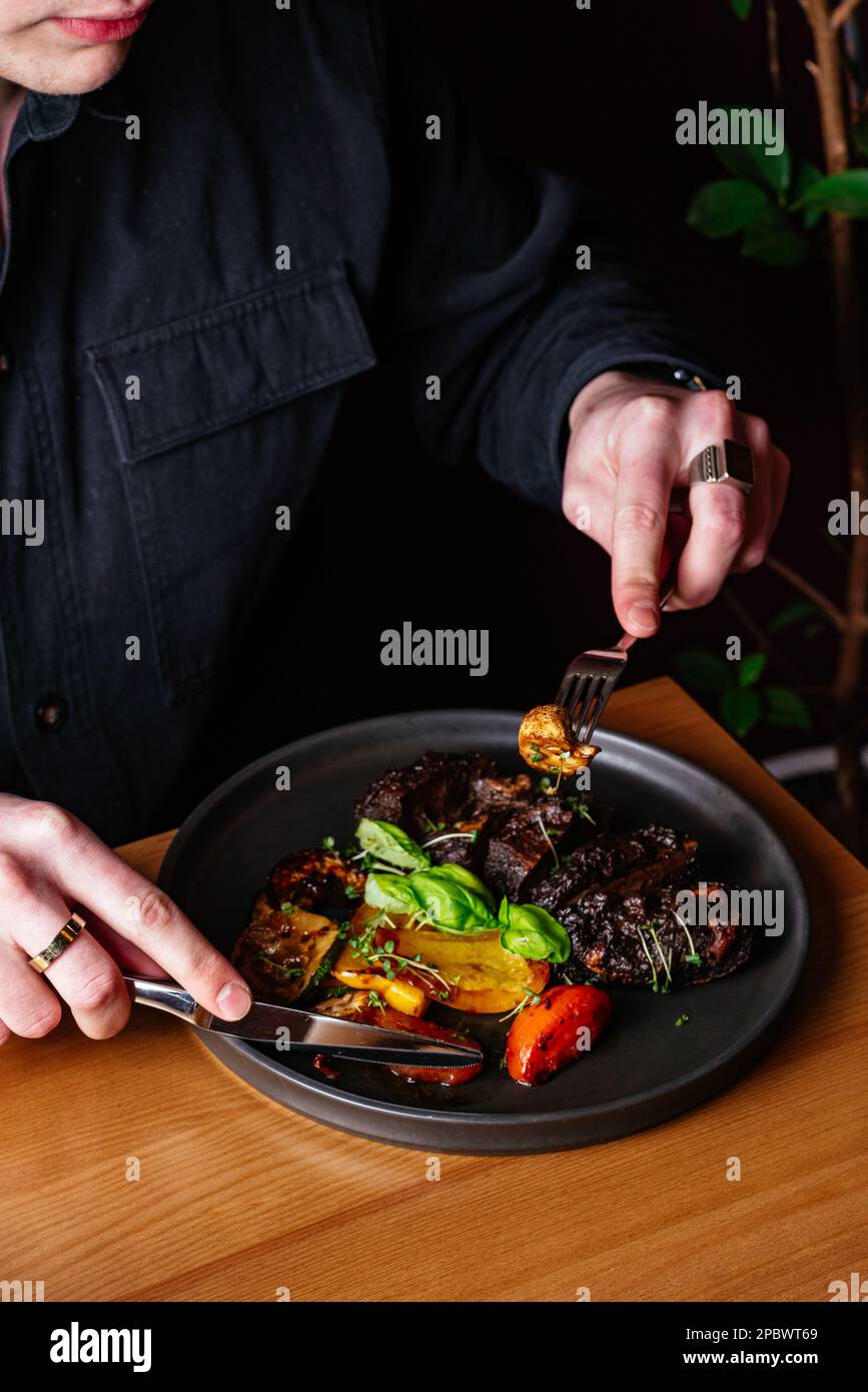 a man eats grilled beef in bbq sauce Stock Photo - Alamy