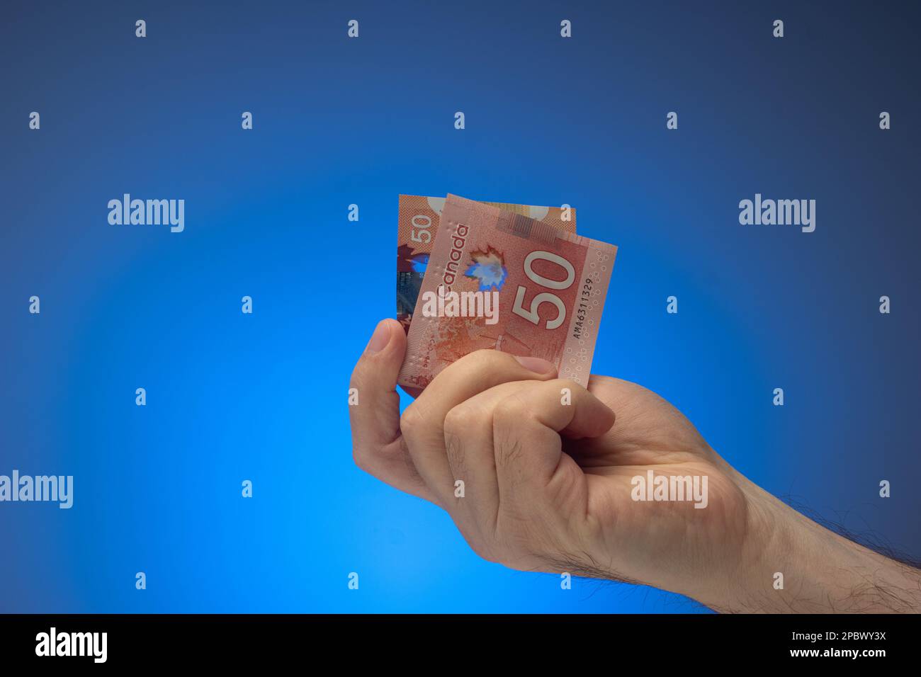 Paper banknote of 50 Canadian dollar bill held between fingers by ...