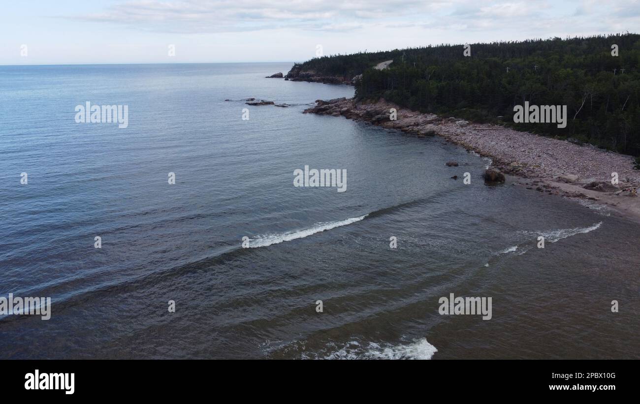 An aerial minimalistic view of the calm sea waves rolling to the shore ...