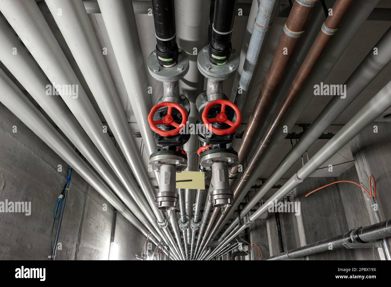 Ceiling mounted industrial pipelines and big round red metal valve ...