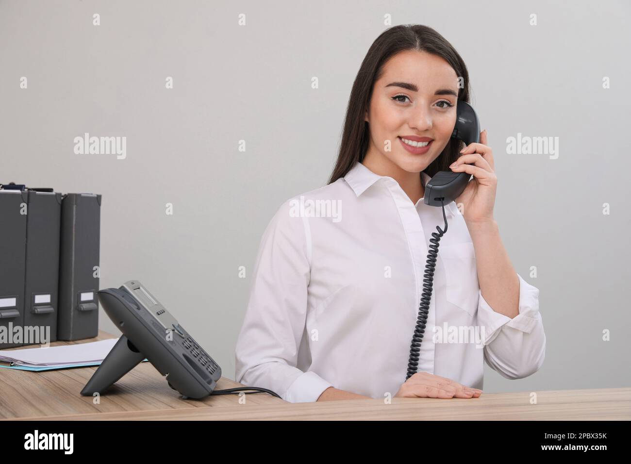 Female receptionist talking on phone at workplace Stock Photo - Alamy