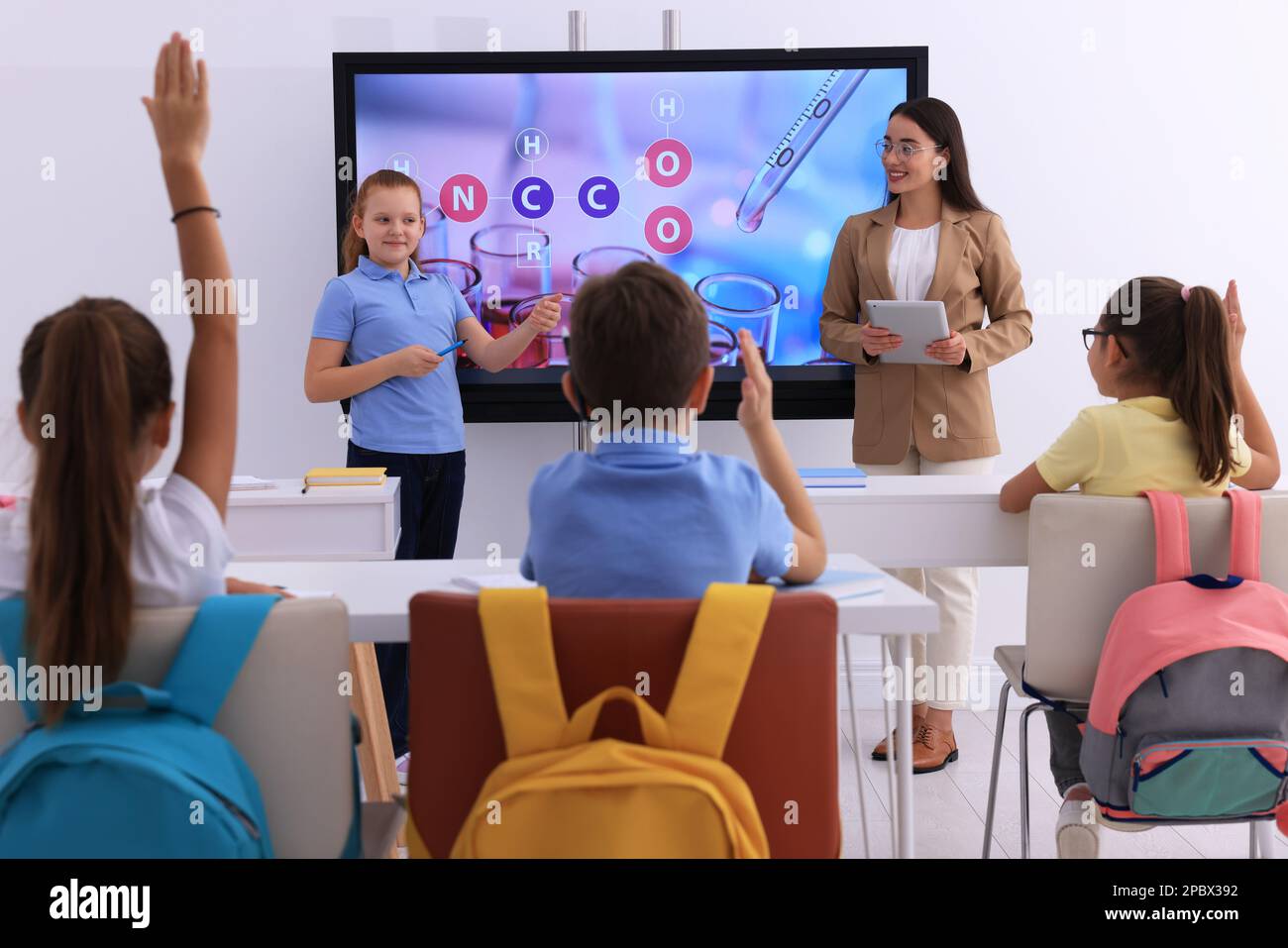 Teacher and pupil using interactive board in classroom during lesson ...