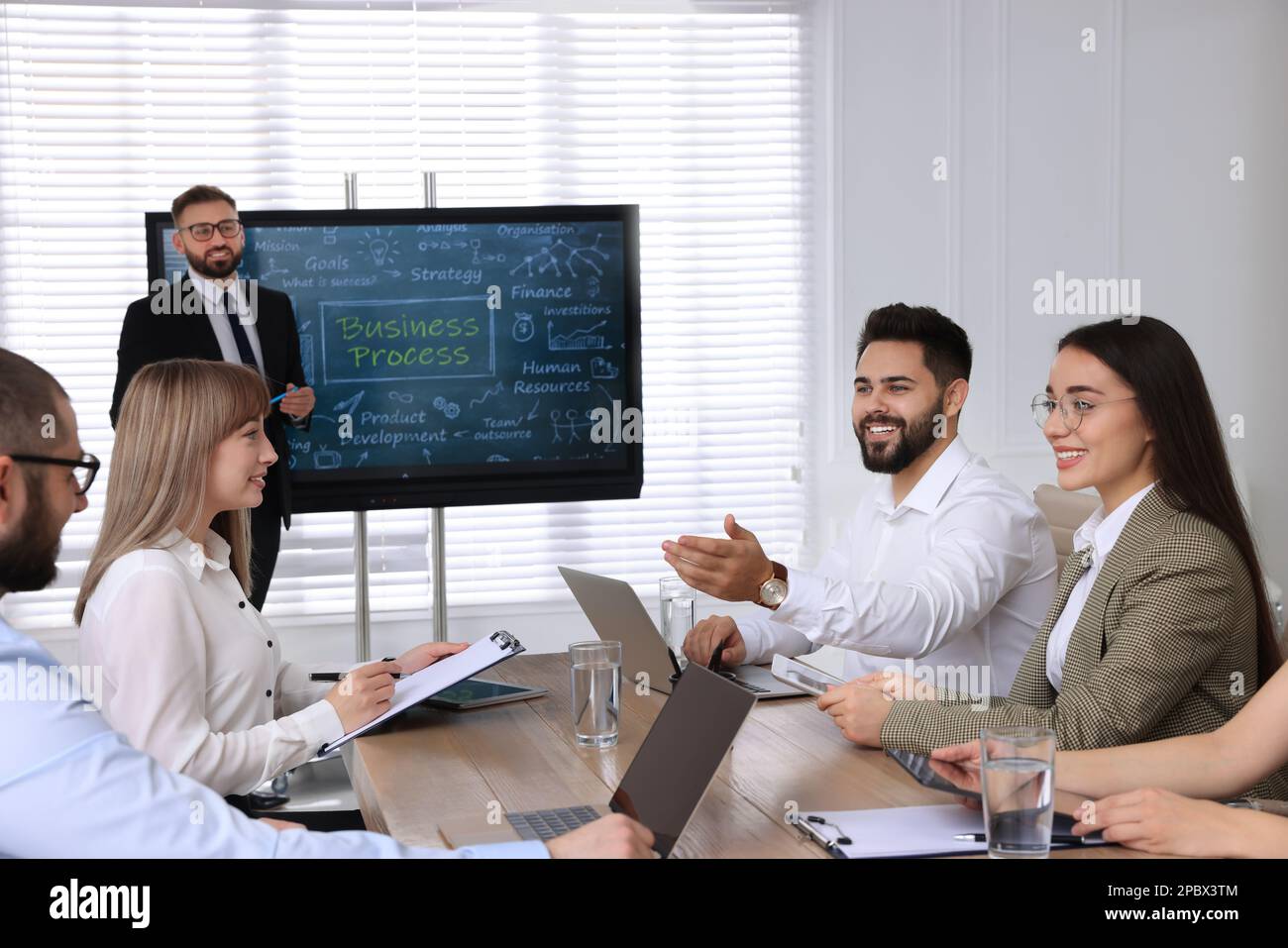 Business trainer near interactive board in meeting room during ...