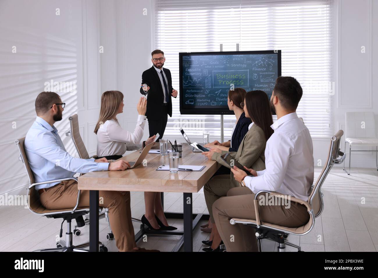 Business trainer near interactive board in meeting room during ...