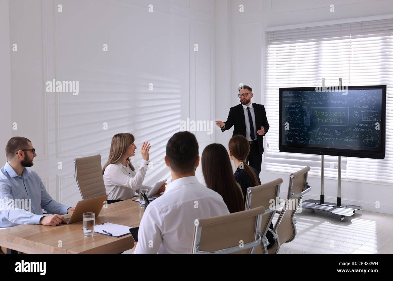 Business trainer near interactive board in meeting room during ...