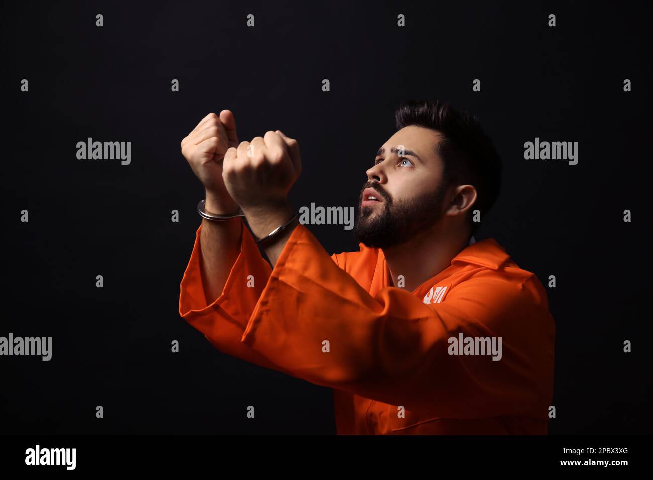 Prisoner in jumpsuit with handcuffs praying on black background Stock ...
