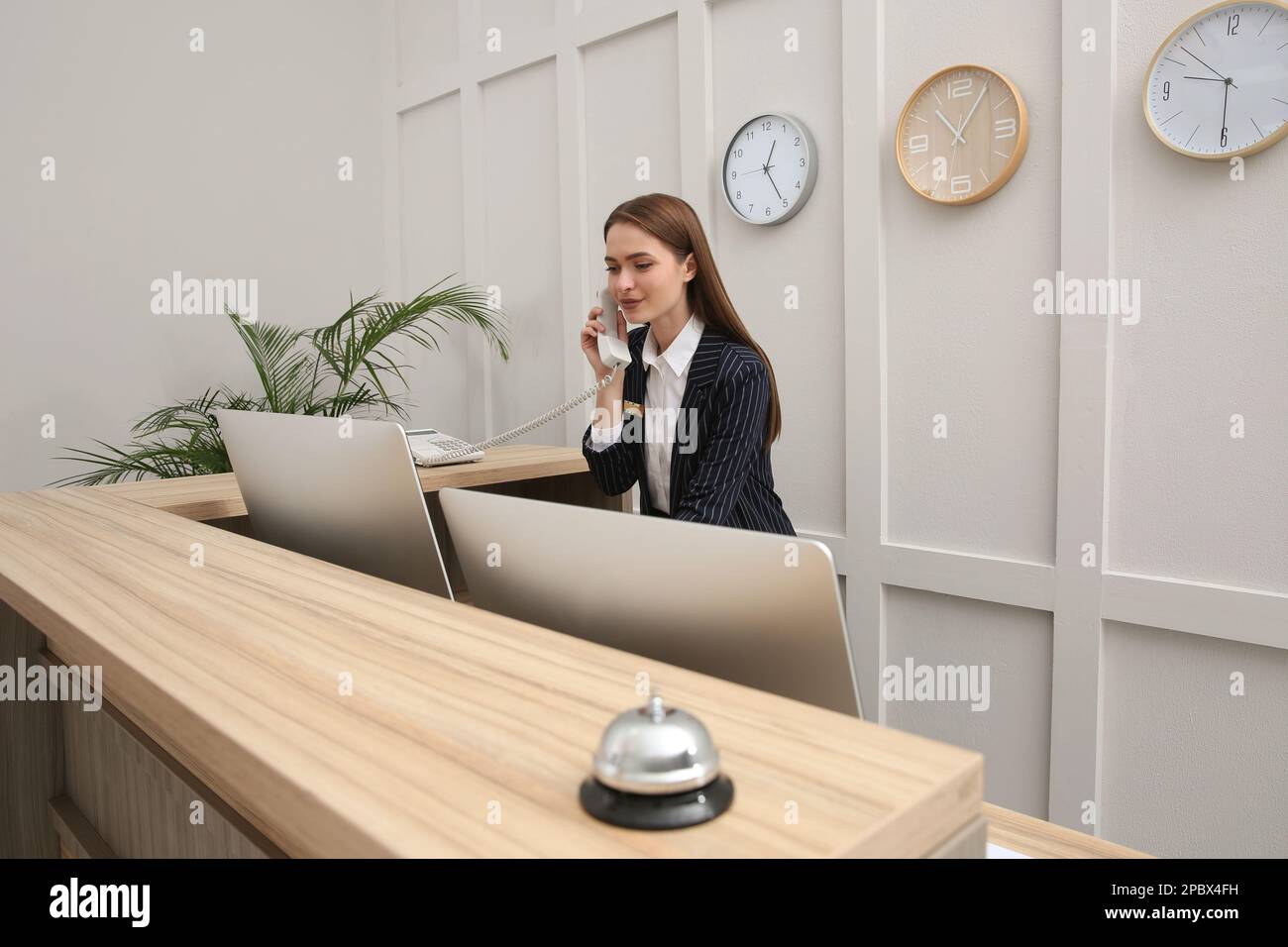 Beautiful receptionist talking on phone at counter in hotel Stock Photo ...
