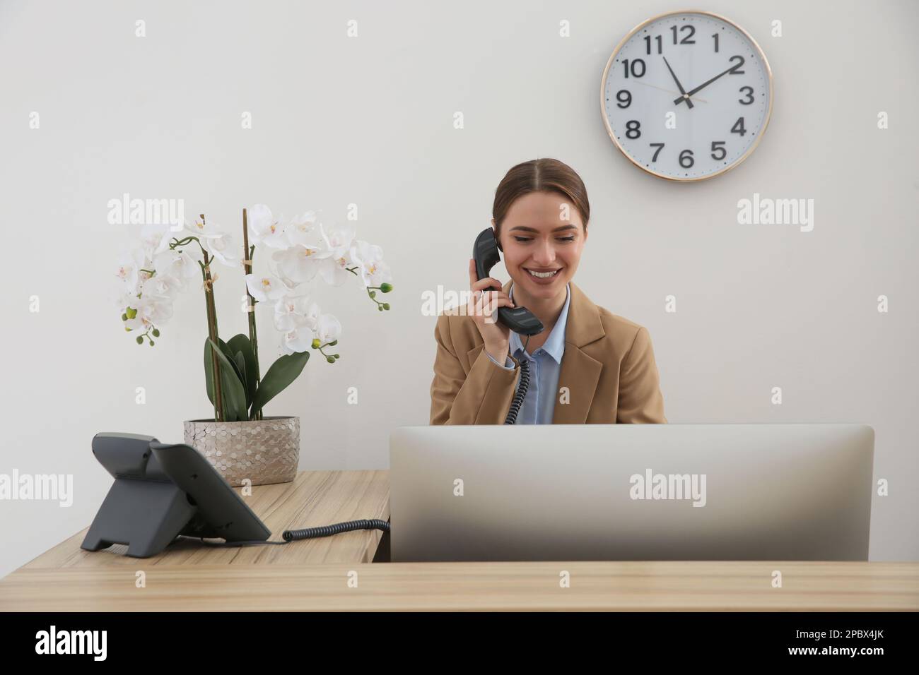 Beautiful receptionist talking on phone at counter in hotel Stock Photo ...