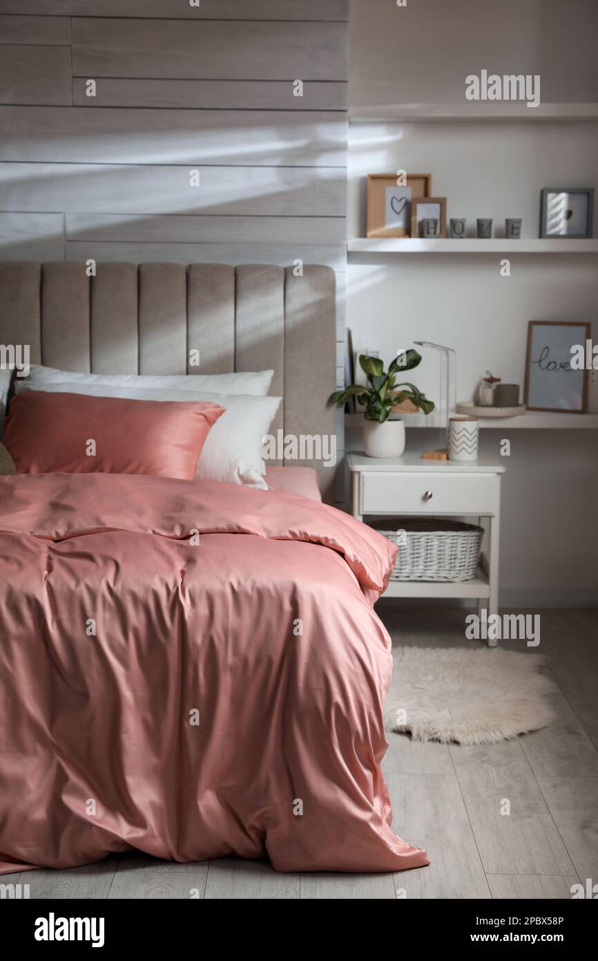 Bed with beautiful silky linens in stylish room interior Stock Photo ...
