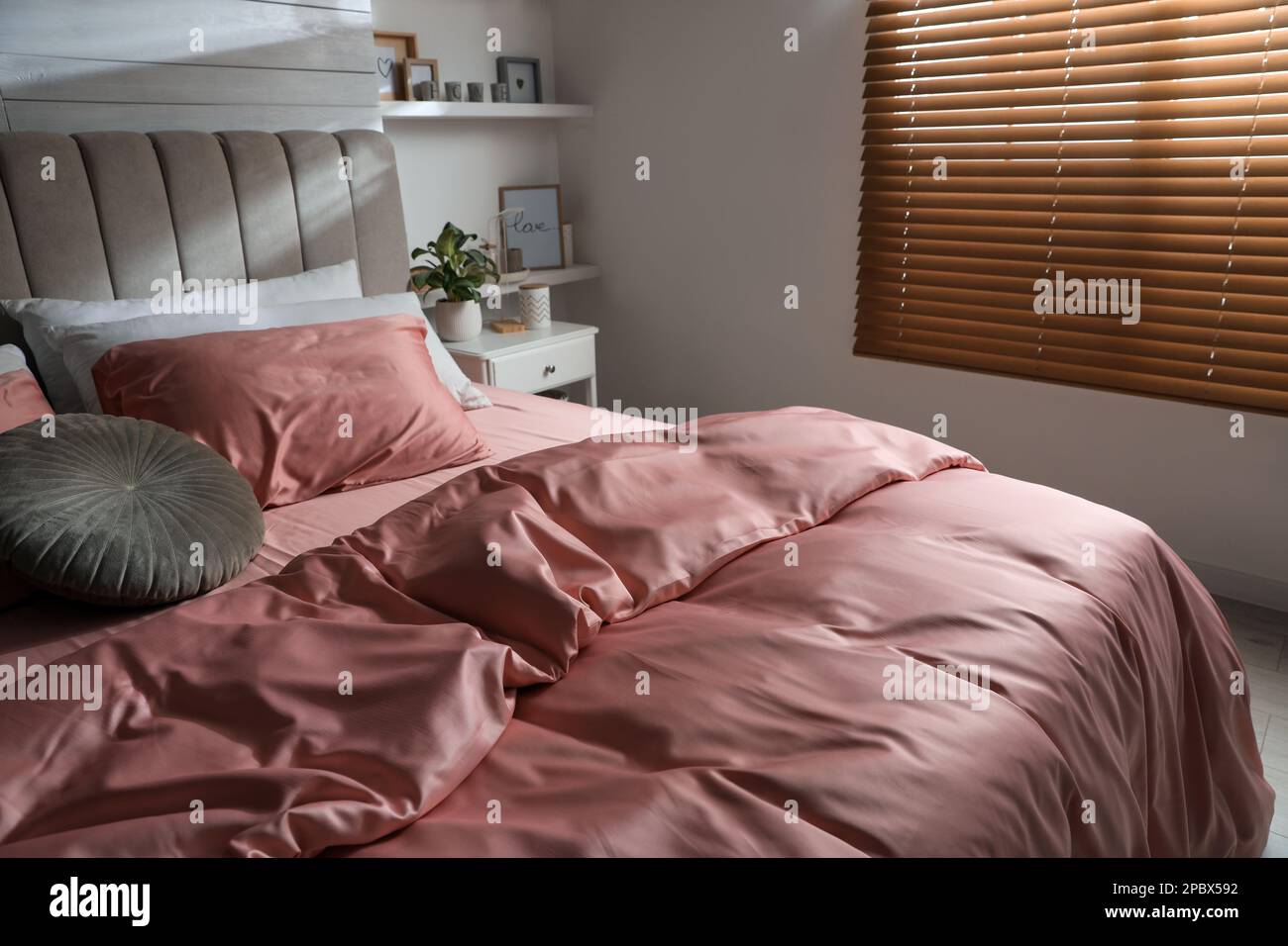 Bed with beautiful silky linens in stylish room interior Stock Photo ...