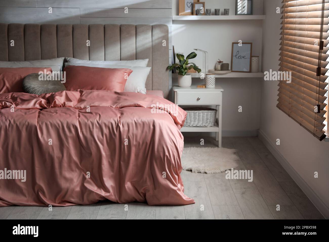 Bed with beautiful silky linens in stylish room interior Stock Photo ...