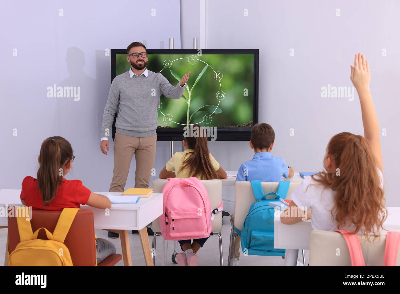 Teacher giving lesson to pupils near interactive board in classroom ...