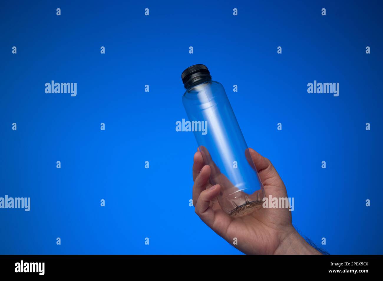 Empty transparent plastic water bottle with cap held in hand by ...