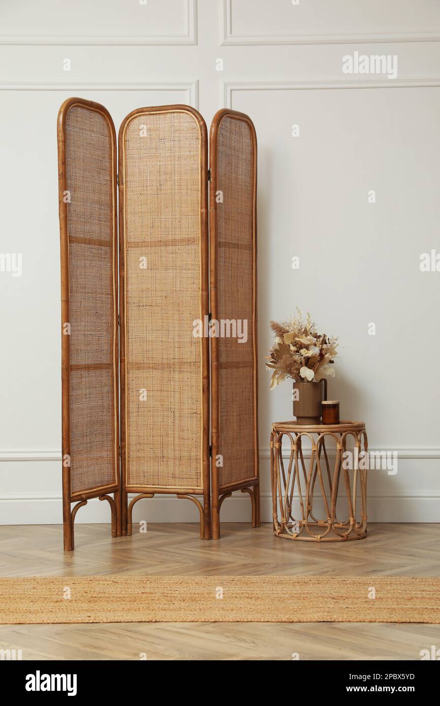Folding screen and small table with flowers in room. Interior design ...