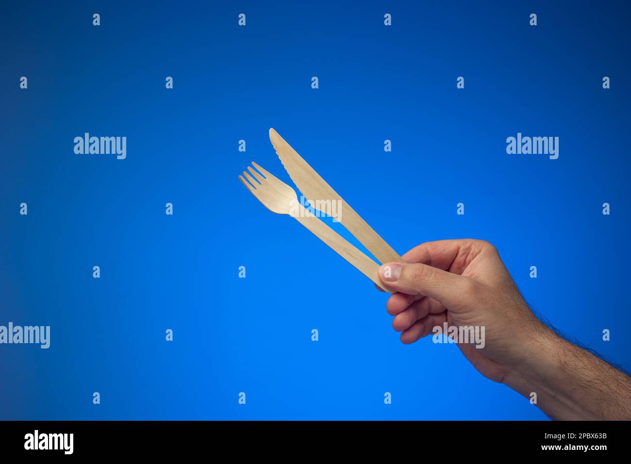 Single use disposable and biodegradable wooden knife and fork held in ...