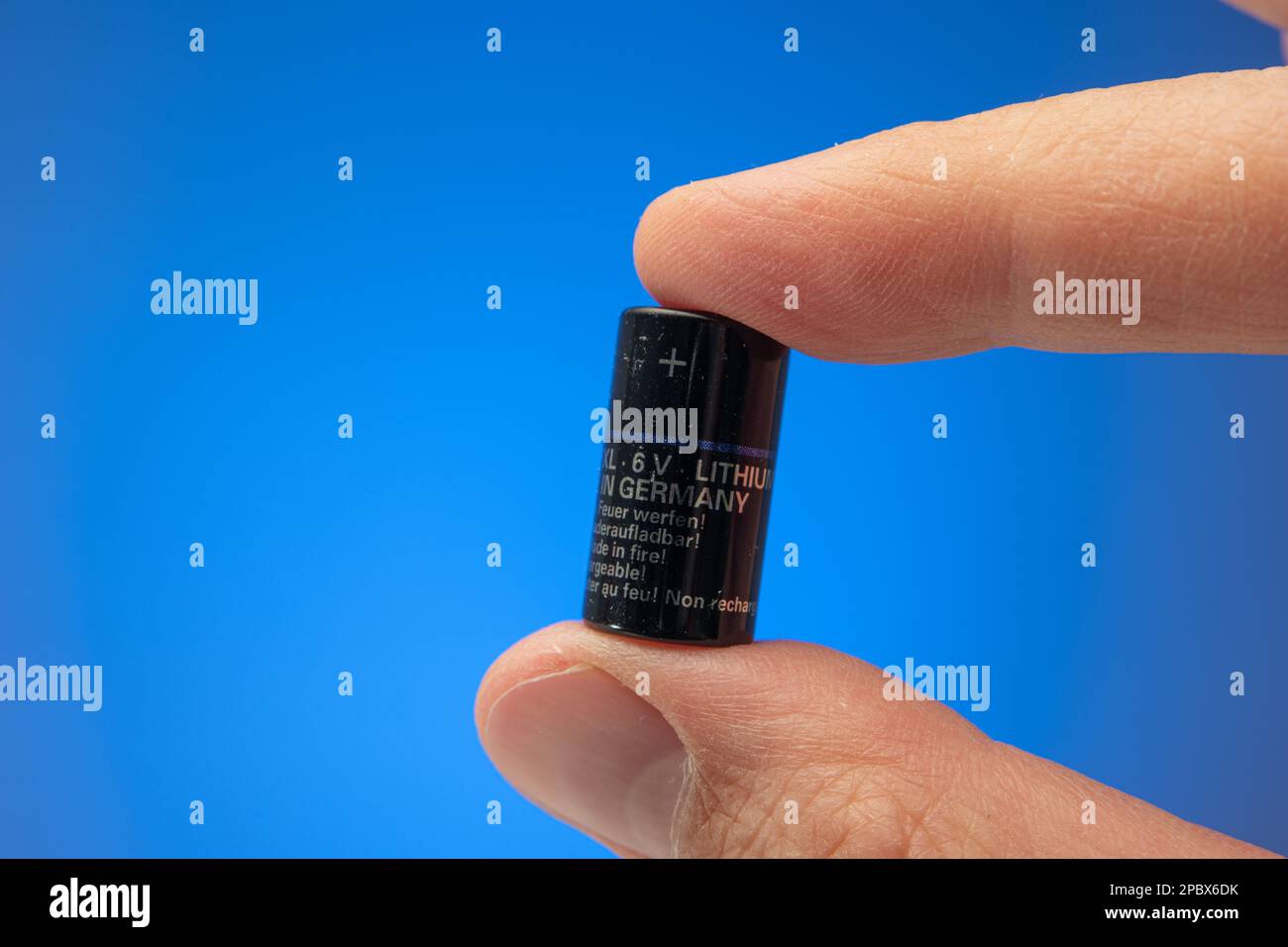 Small cylindrical PX28 Alcaline battery held between fingers by ...