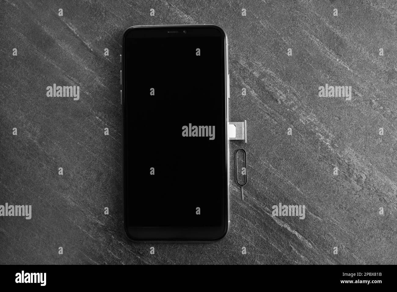 Mobile phone with Sim card in tray and ejector tool on grey table, flat ...