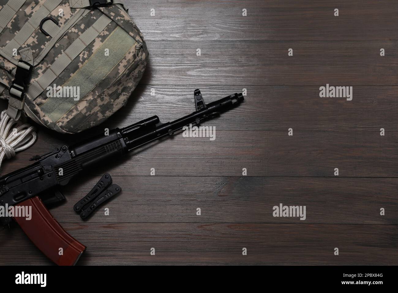 Flat lay composition with gun and military knapsack on wooden table ...