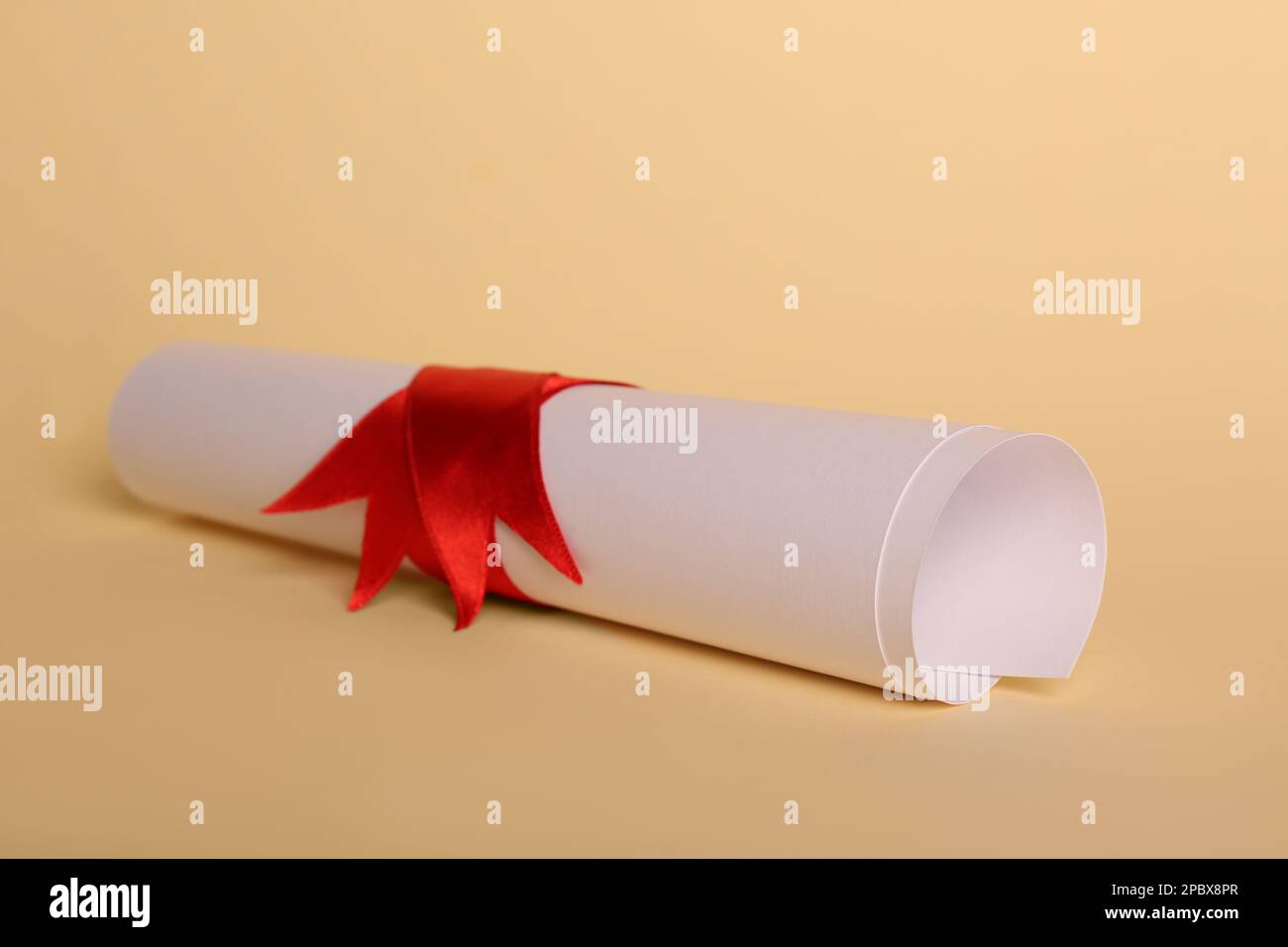 Rolled student's diploma with red ribbon on beige background Stock ...