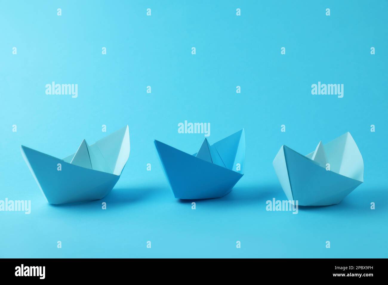 Handmade paper boats on light blue background. Origami art Stock Photo ...