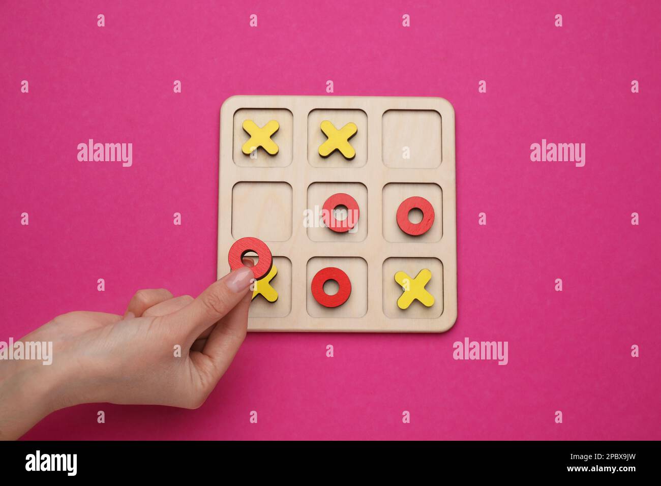 Woman playing tic tac toe game on bright pink background, top view ...