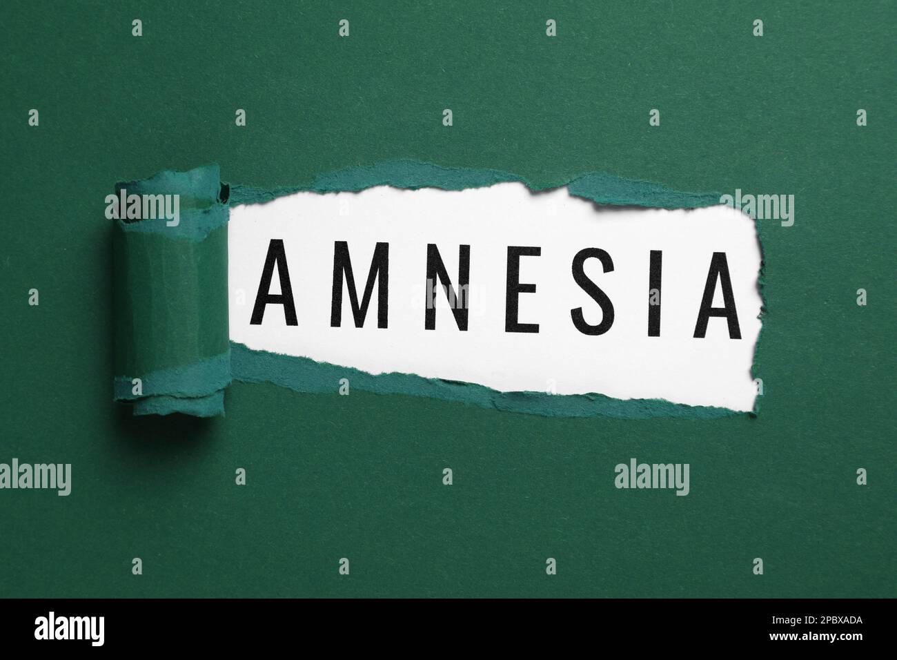 Word Amnesia on white background, view through hole in green paper ...