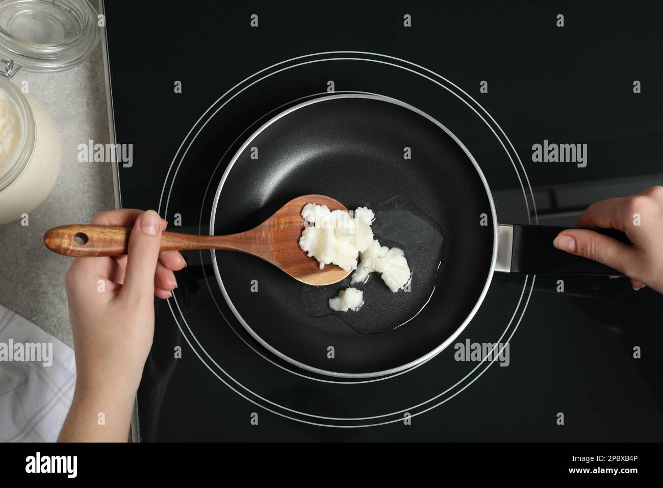 Woman cooking with coconut oil on induction stove, top view Stock Photo ...