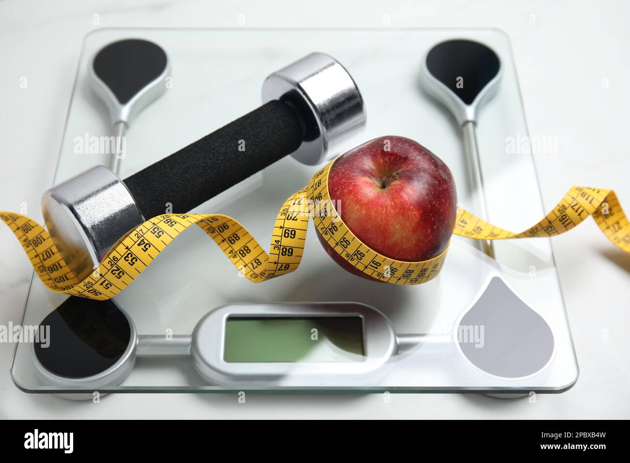 Scales, apple, measuring tape and dumbbell on white table Stock Photo ...