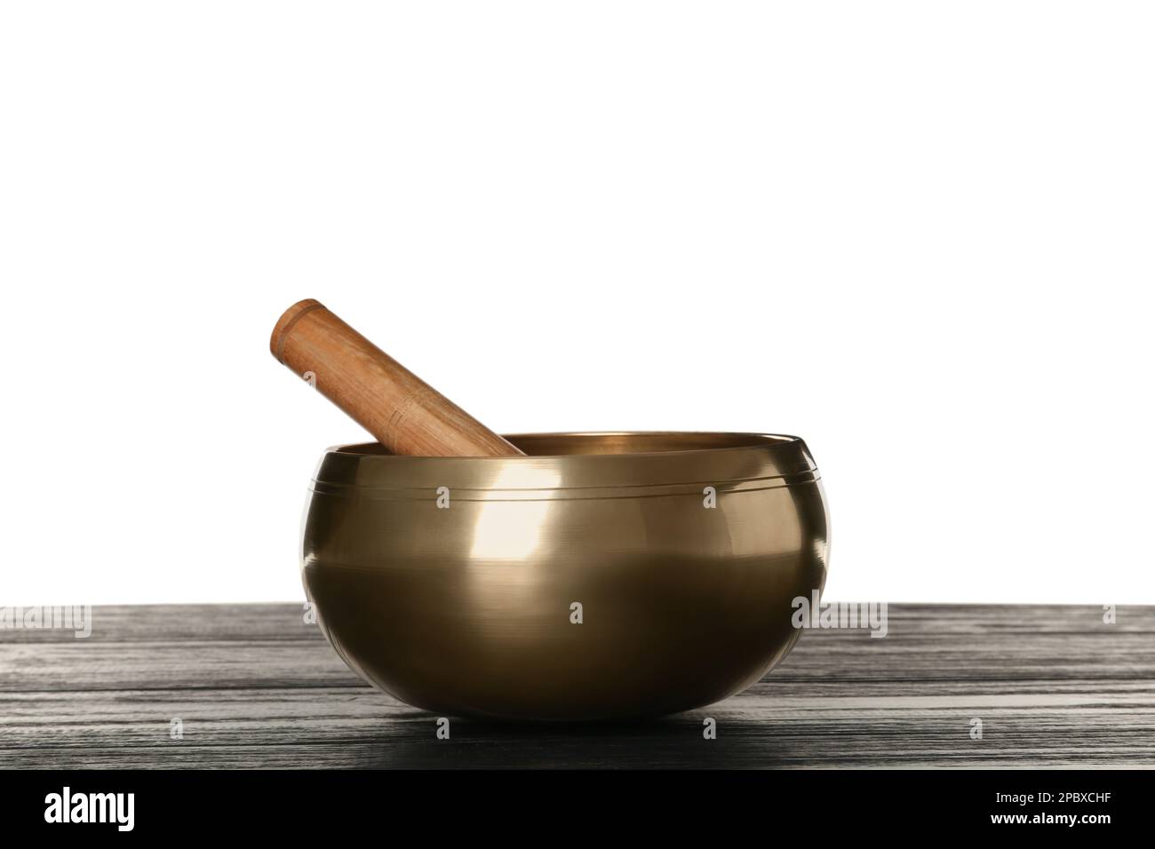 Golden singing bowl and mallet on wooden table against white background ...