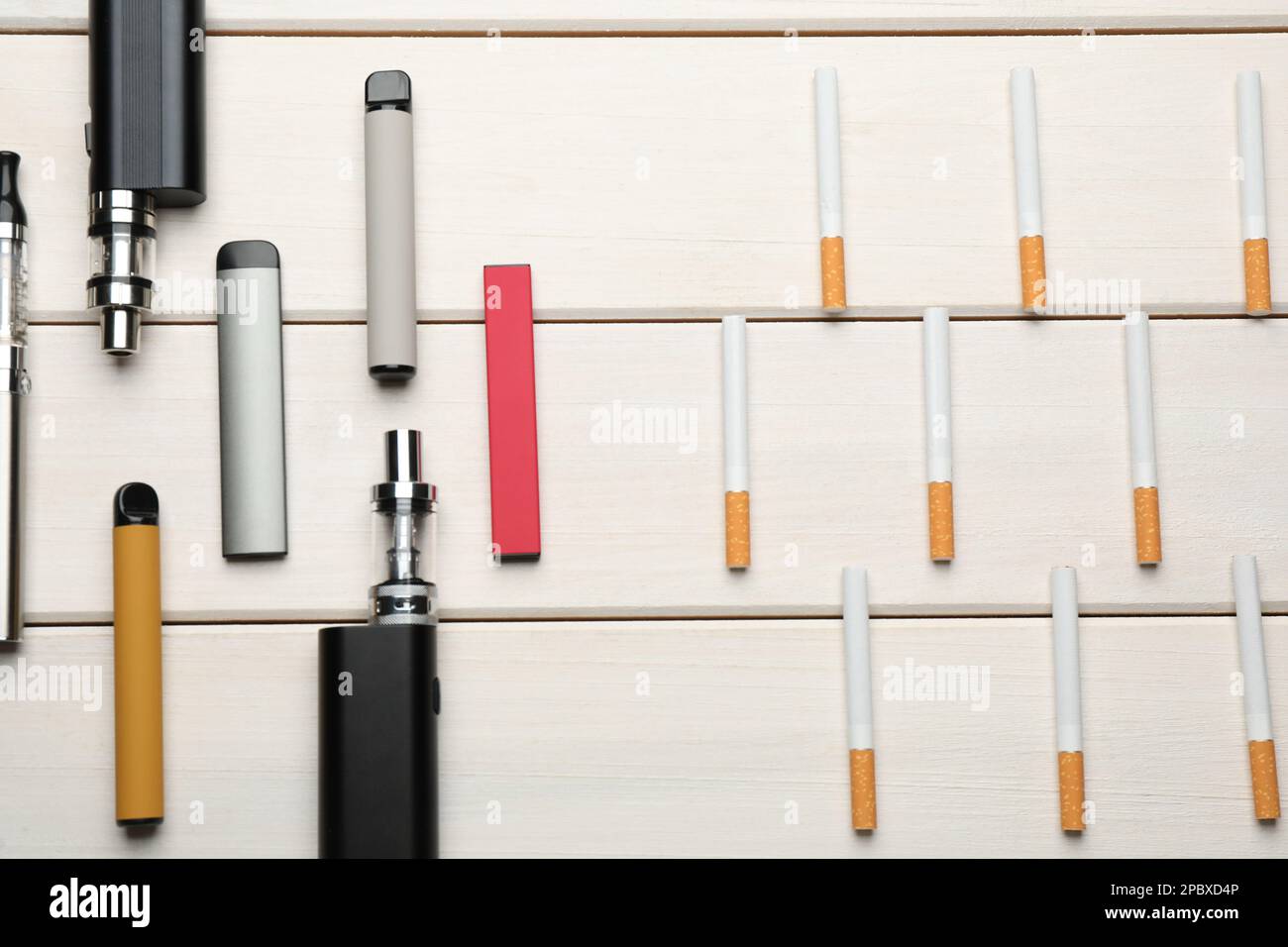 Different vaping devices and cigarettes on white wooden table, flat lay ...