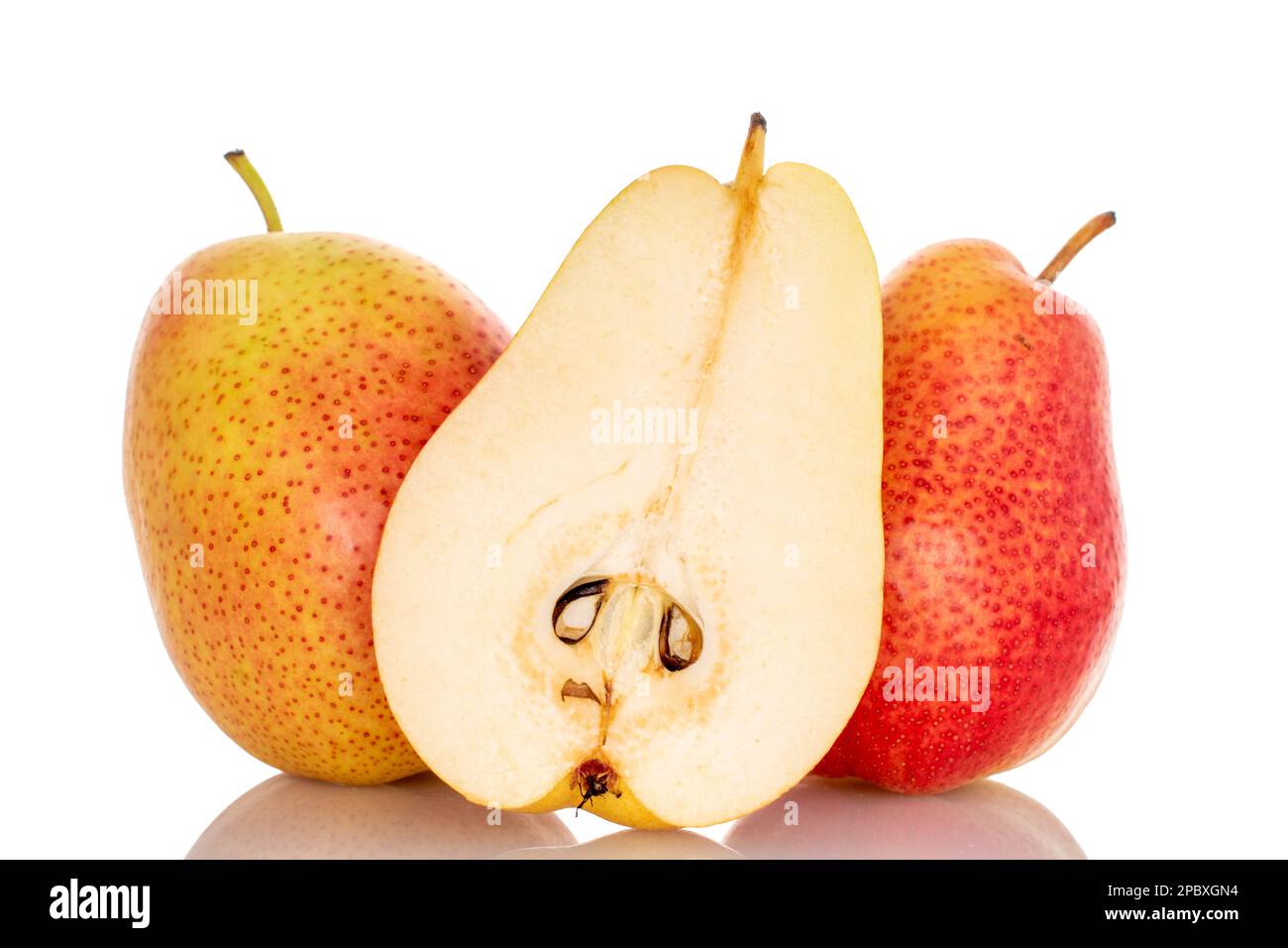 One pear half, in focus, and two whole pears, close-up, on a white ...