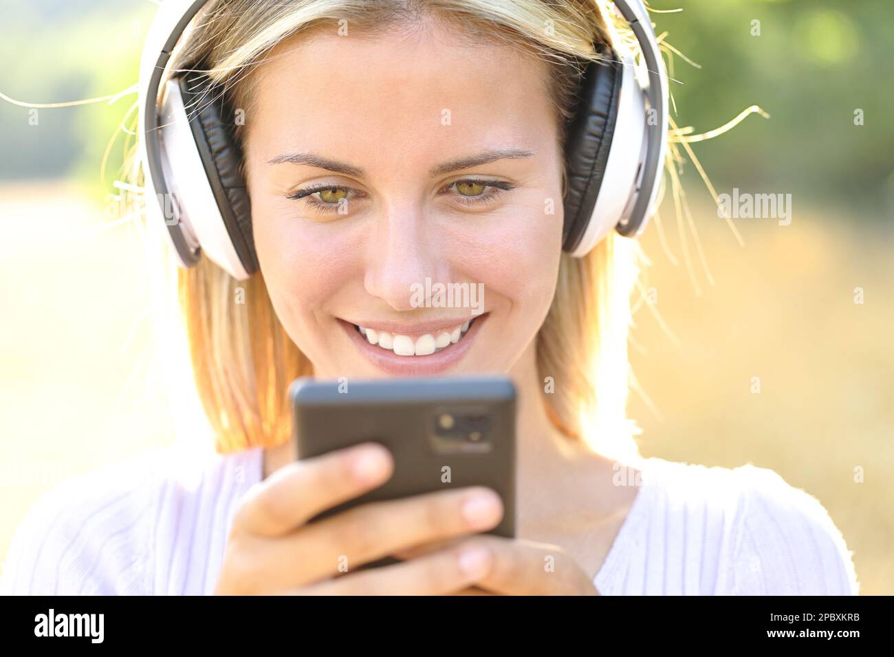 Front view of a happy teen listening to music watching phone content ...