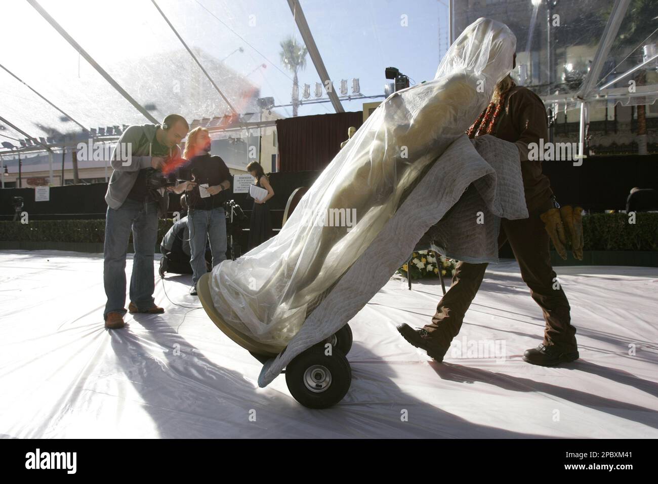 Workman moves a plastic-wrapped Oscar statue outside the Kodak Theatre ...