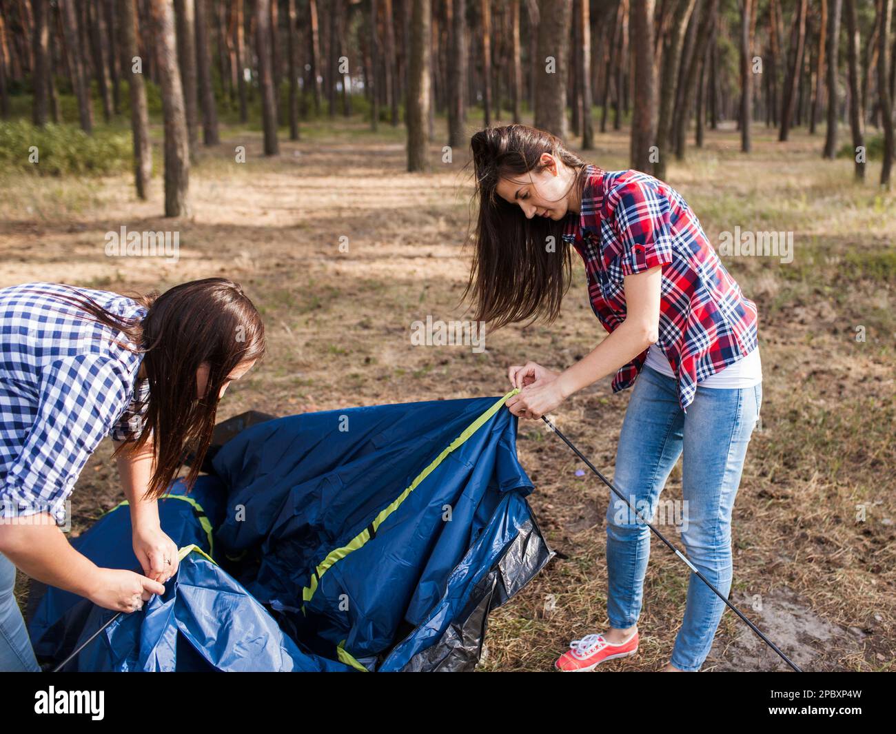 Friend help support set up tent together Stock Photo - Alamy