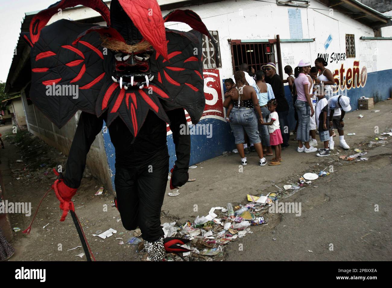 Residents line up in a shop as a man disguised as the devil walks ...