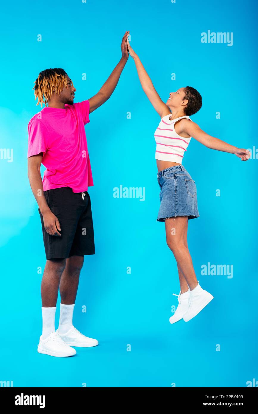 Side view of positive young ethnic female in casual clothes jumping for ...