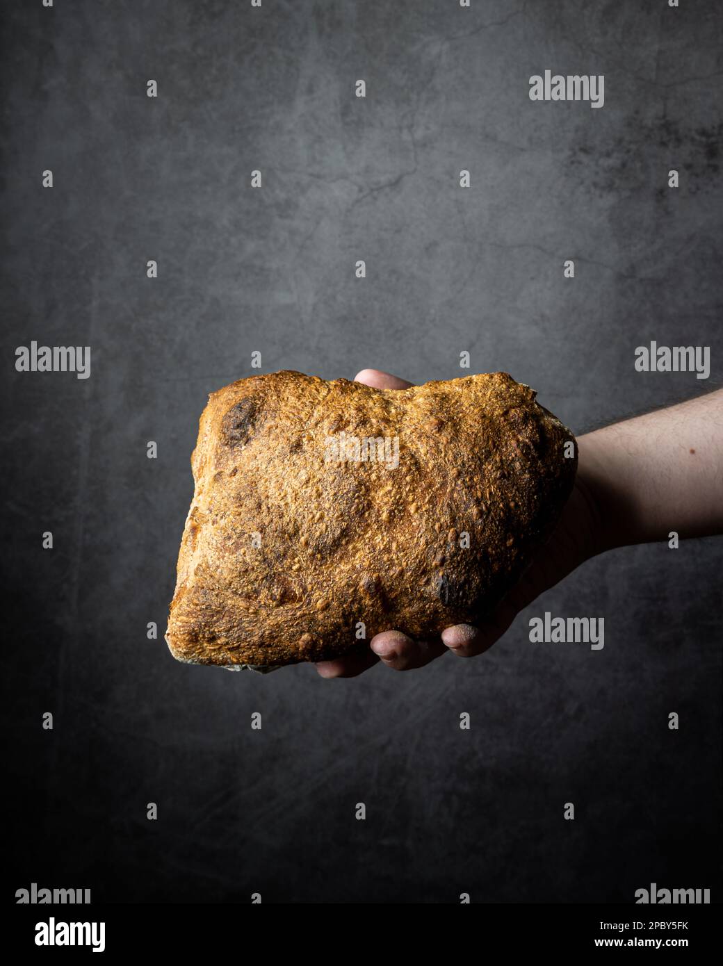 Hand of crop anonymous person holding fresh backed aromatic bread with ...
