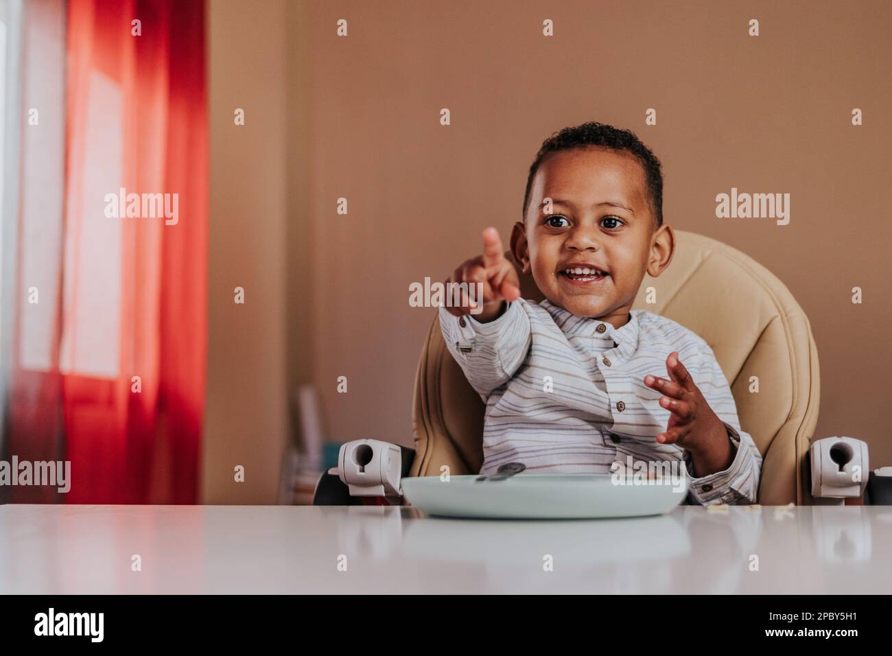 Cute black toddler with plate of delicious food looking away and ...