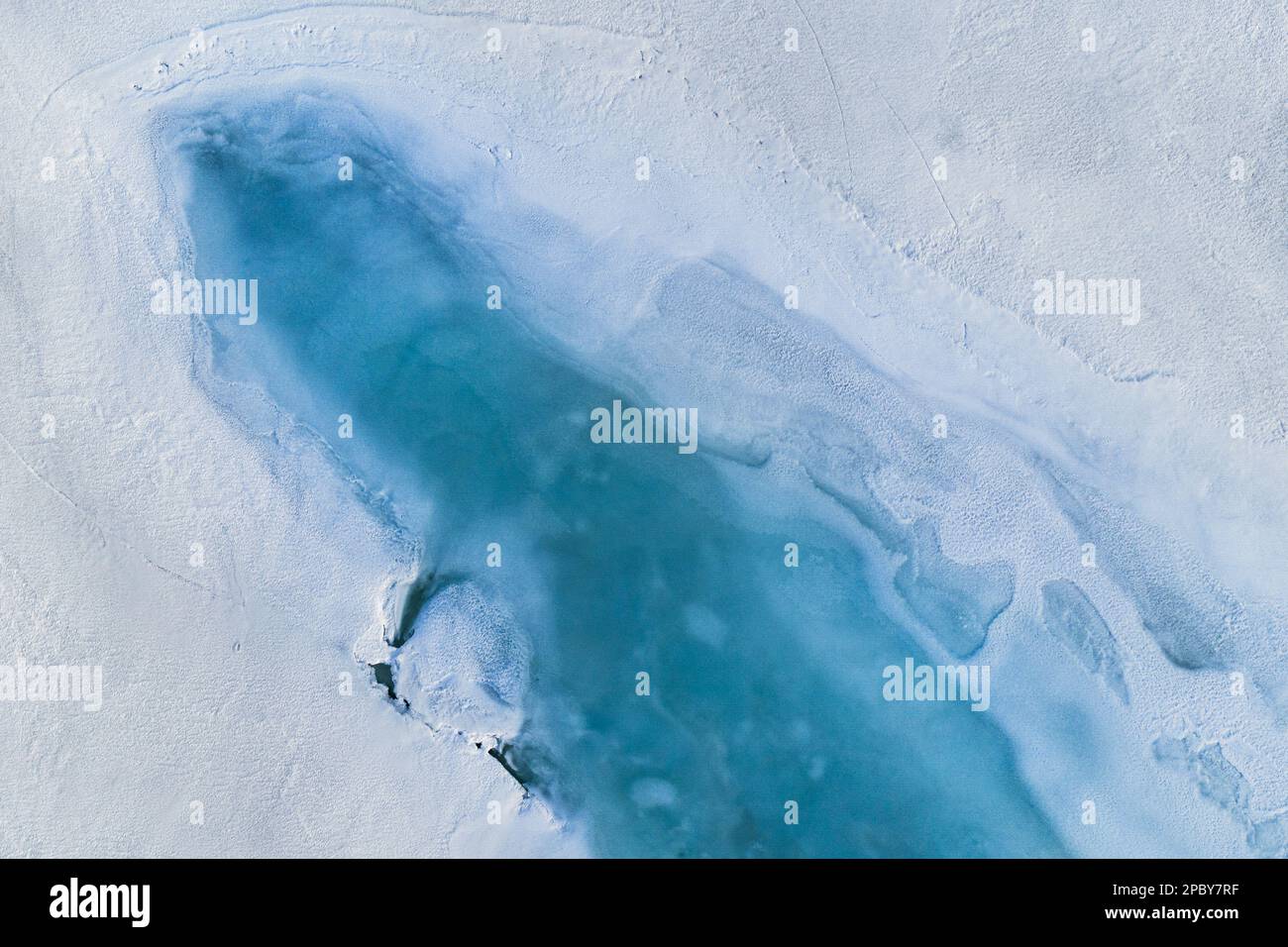 Textured background of blue ice on smooth surface of frozen lake water ...