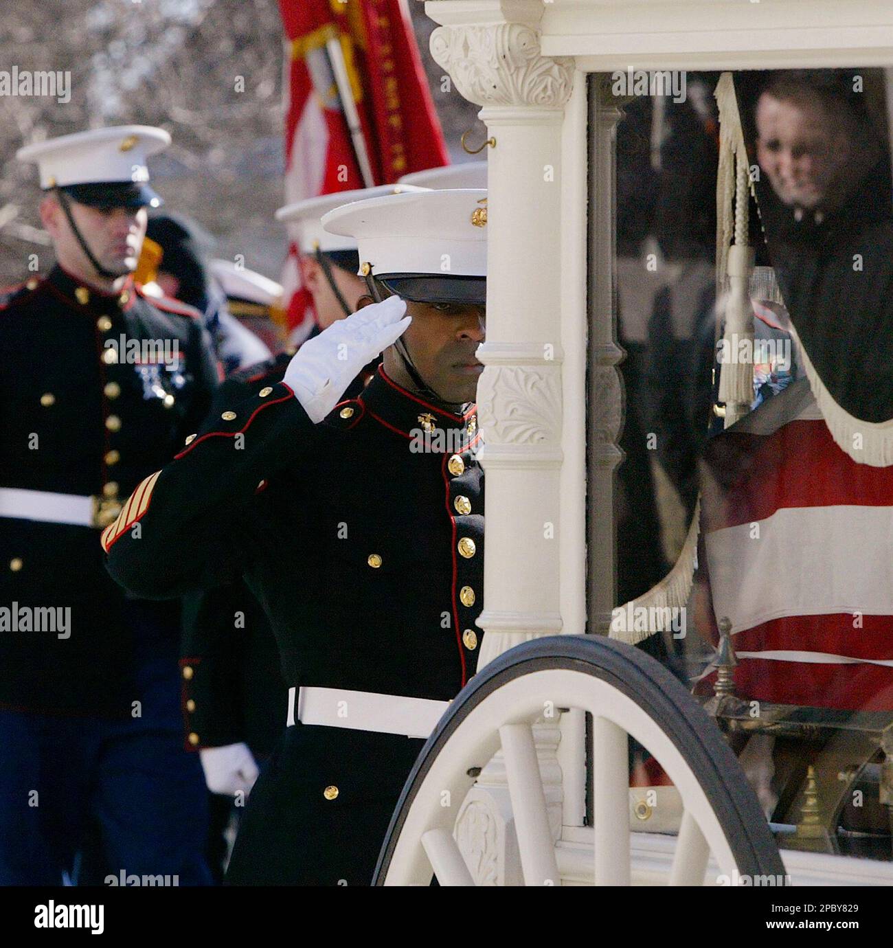 A member of a U.S. Marine Corps honor guard salutes a flag-draped ...