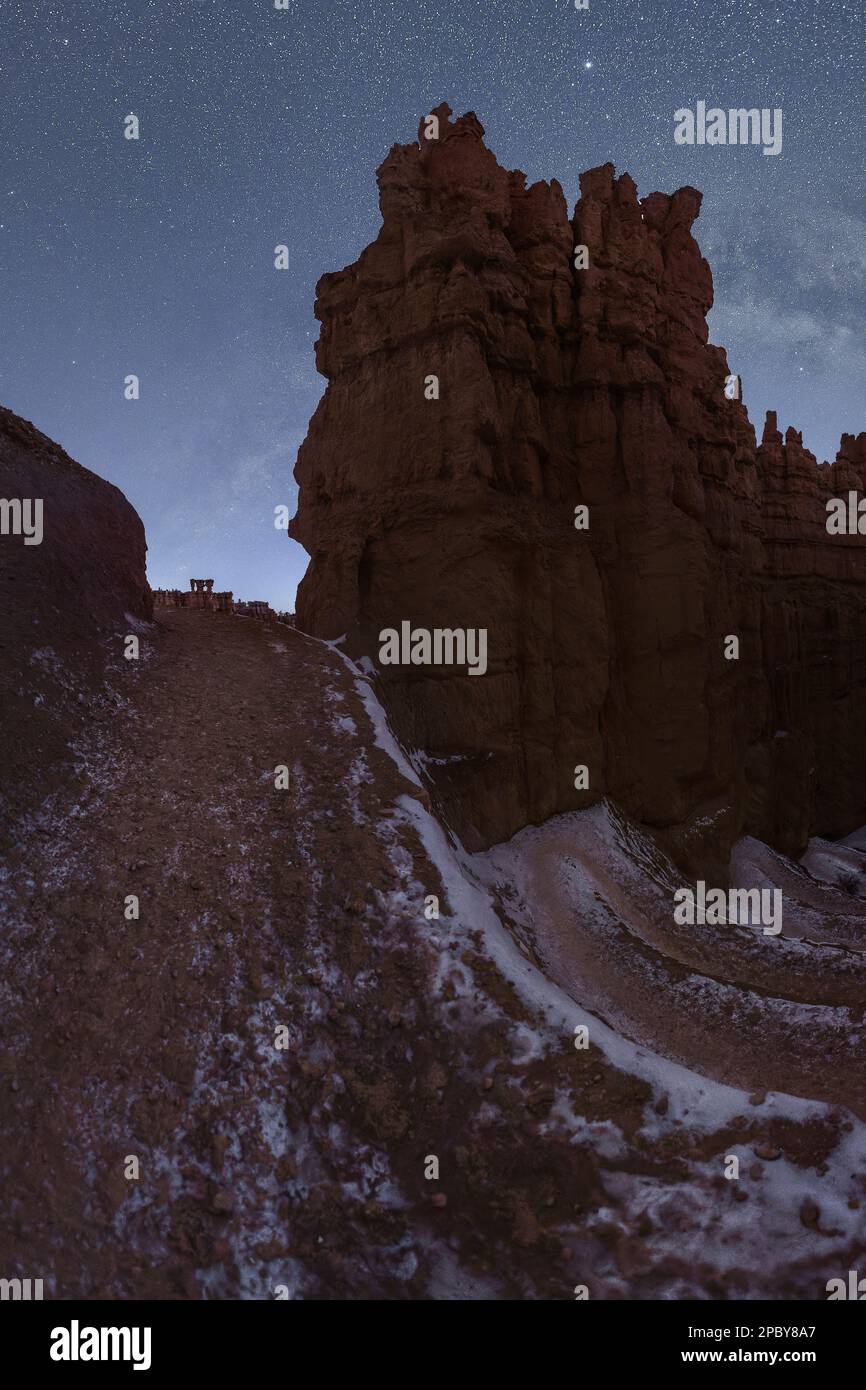 From below of rough rocky cliff with uneven surface and mountains under ...