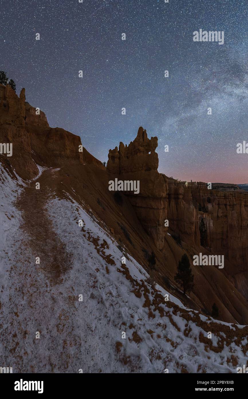 From below of rough rocky cliff with uneven surface and mountains under ...