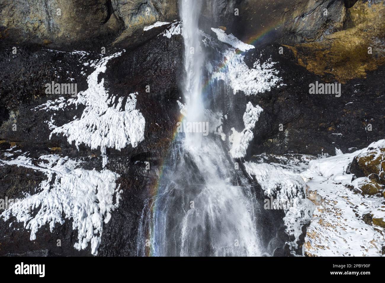 Breathtaking waterfall creating rainbow falling from rough rocky cliff ...