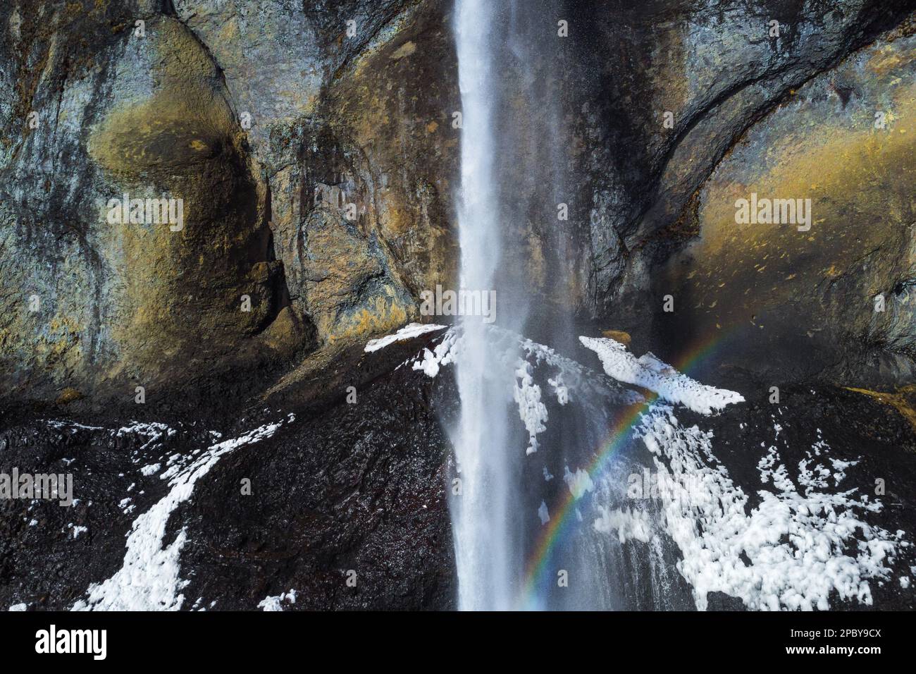 Breathtaking waterfall creating rainbow falling from rough rocky cliff ...