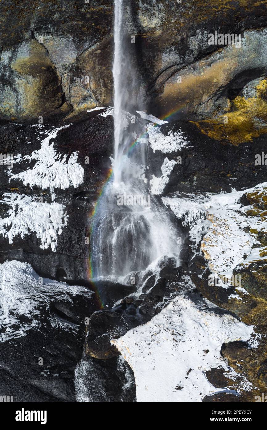 Breathtaking waterfall creating rainbow falling from rough rocky cliff ...