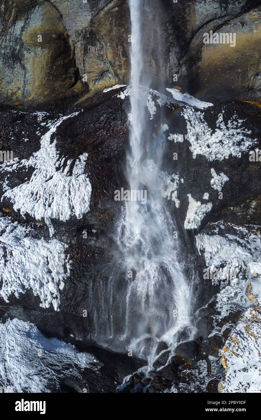 Breathtaking waterfall creating rainbow falling from rough rocky cliff ...