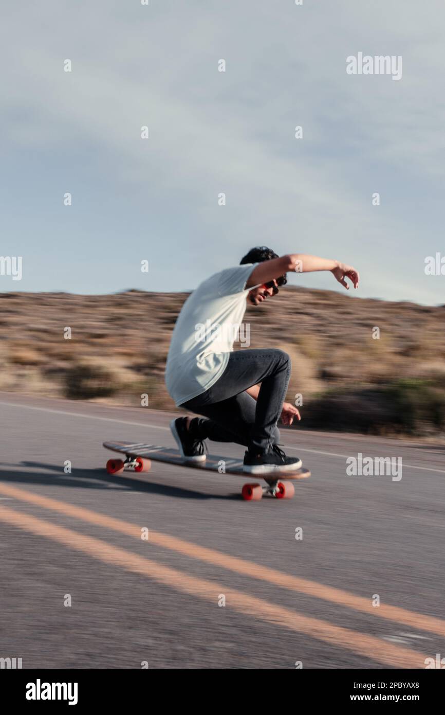 Full body of male skater in casual clothes performing extreme trick on ...