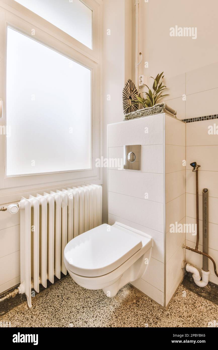 Interior of modern bathroom with wall mounted toilet and radiator near ...